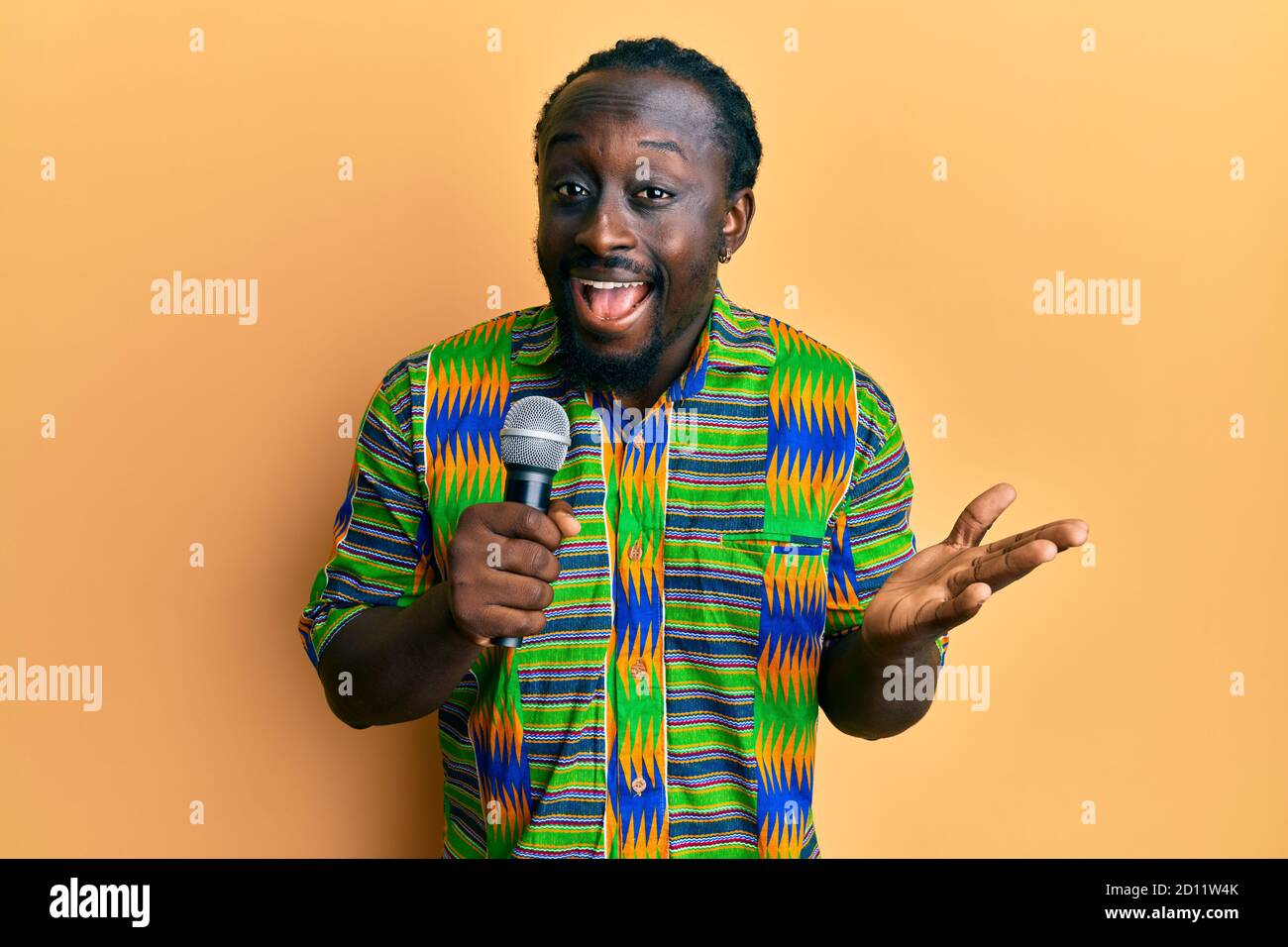 Handsome young black man singing song using microphone celebrating ...