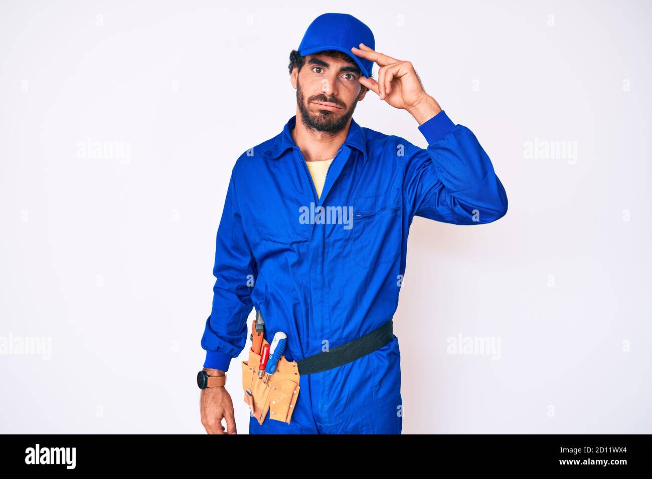 Handsome young man with curly hair and bear weaing handyman uniform ...