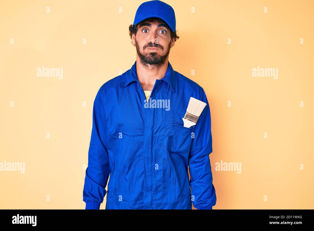 Handsome young man with curly hair and bear wearing builder jumpsuit ...
