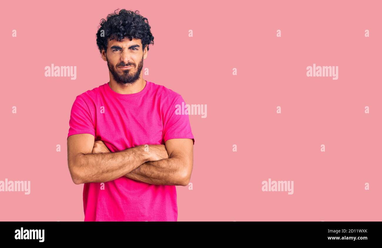 Handsome young man with curly hair and bear wearing casual pink tshirt ...