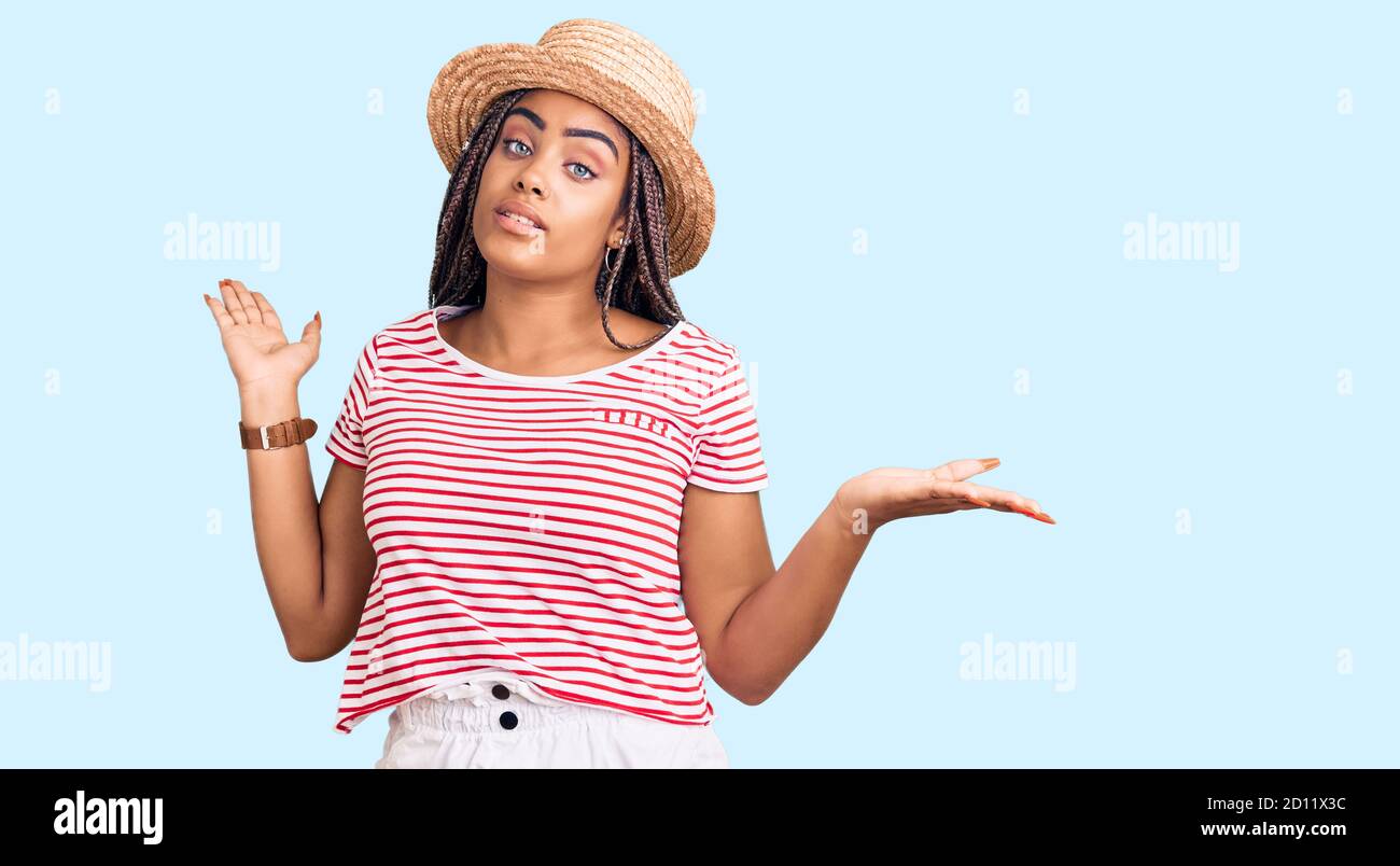 Young african american woman with braids wearing summer hat clueless ...