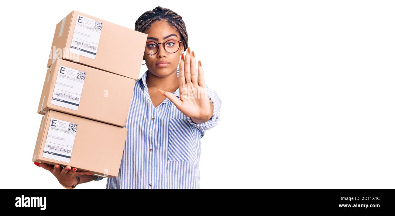 Young african american woman with braids holding delivery packages with ...