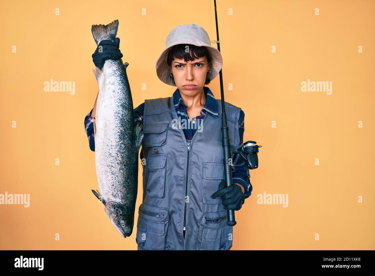 Beautiful brunettte fisher woman holding fishing rod and raw salmon ...