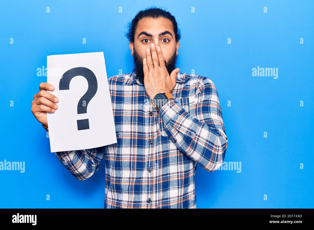 Young arab man holding question mark covering mouth with hand, shocked ...