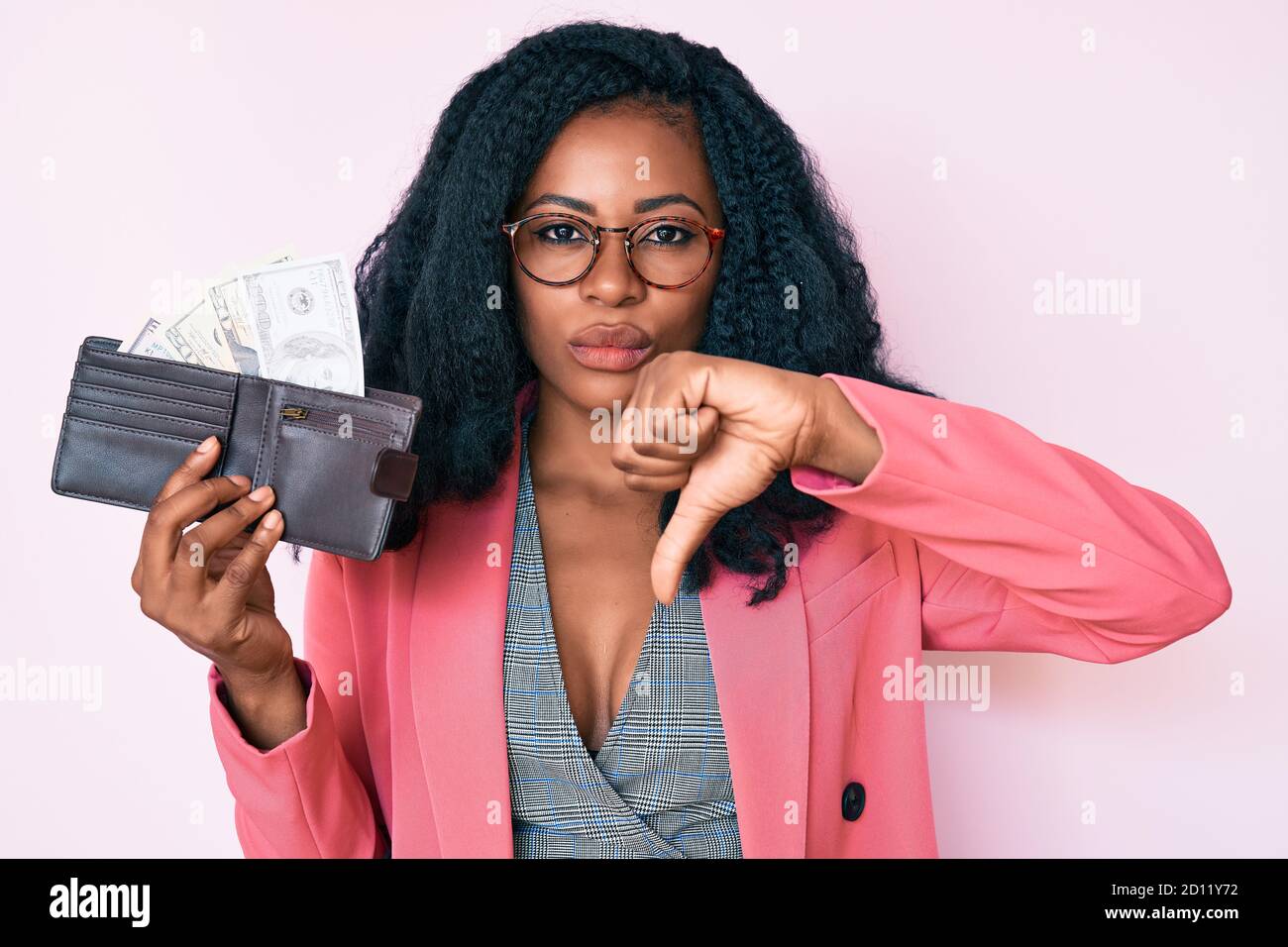 Beautiful african woman holding wallet with dollars with angry face ...