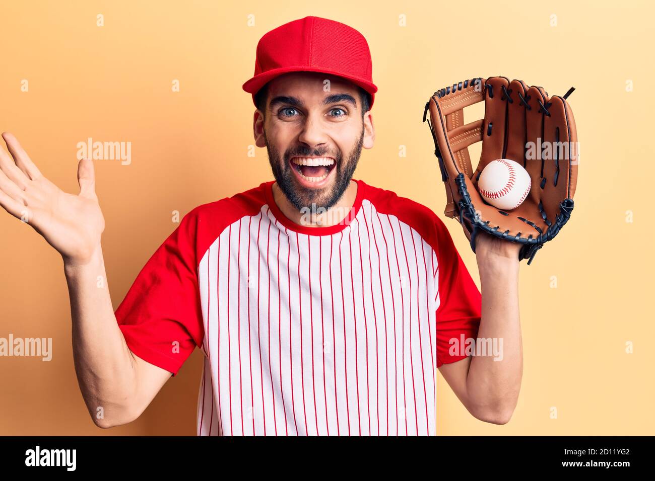 Young handsome man with beard playing baseball using ball and glove ...
