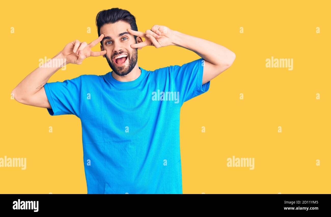 Young handsome man with beard wearing casual t-shirt doing peace symbol ...