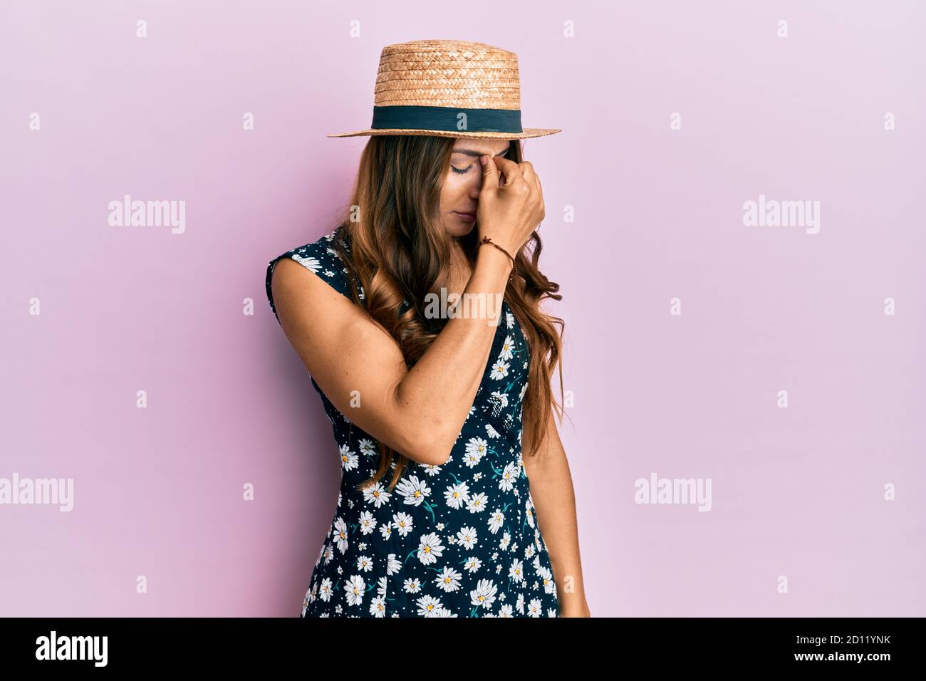 Young brunette woman wearing summer hat tired rubbing nose and eyes ...