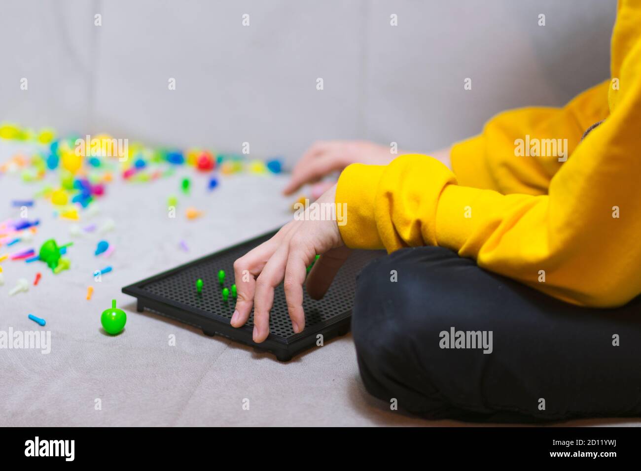 Child playing creative pin board game with colorful plasitc peaces ...