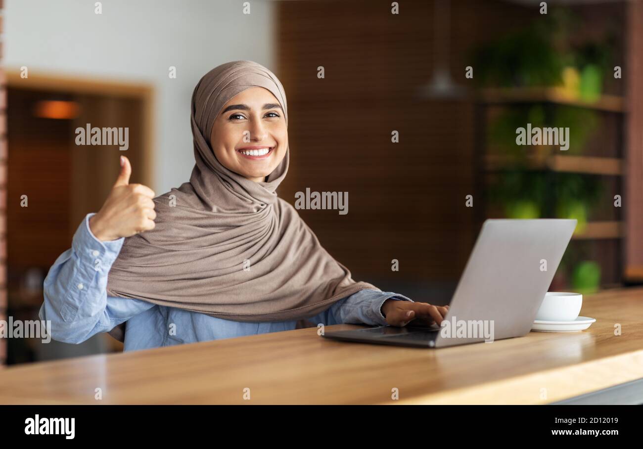 Happy muslim woman in hijab working online at cafe Stock Photo - Alamy