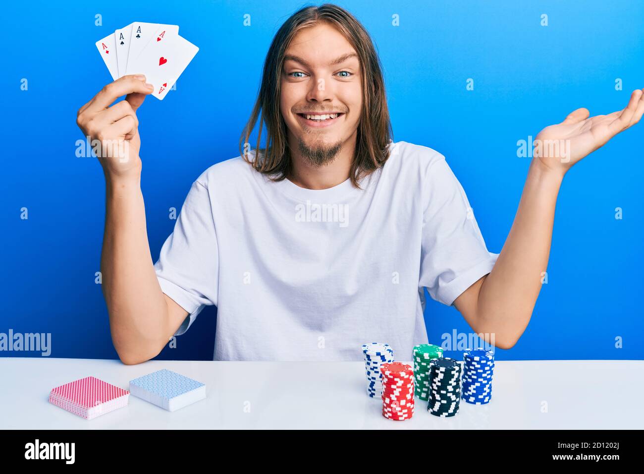Handsome caucasian man with long hair playing poker holding cards ...