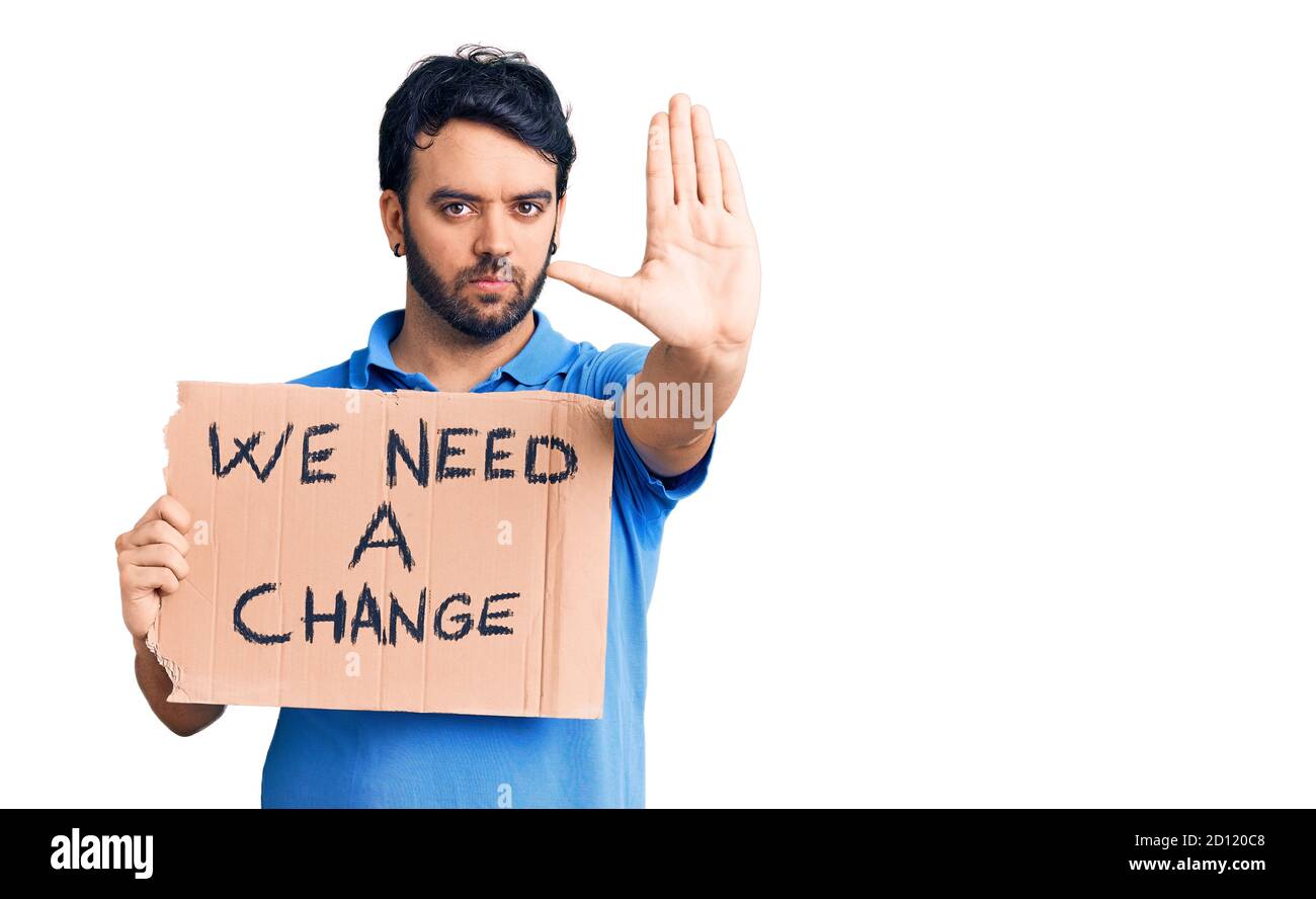 Young hispanic man holding we need a change banner with open hand doing ...