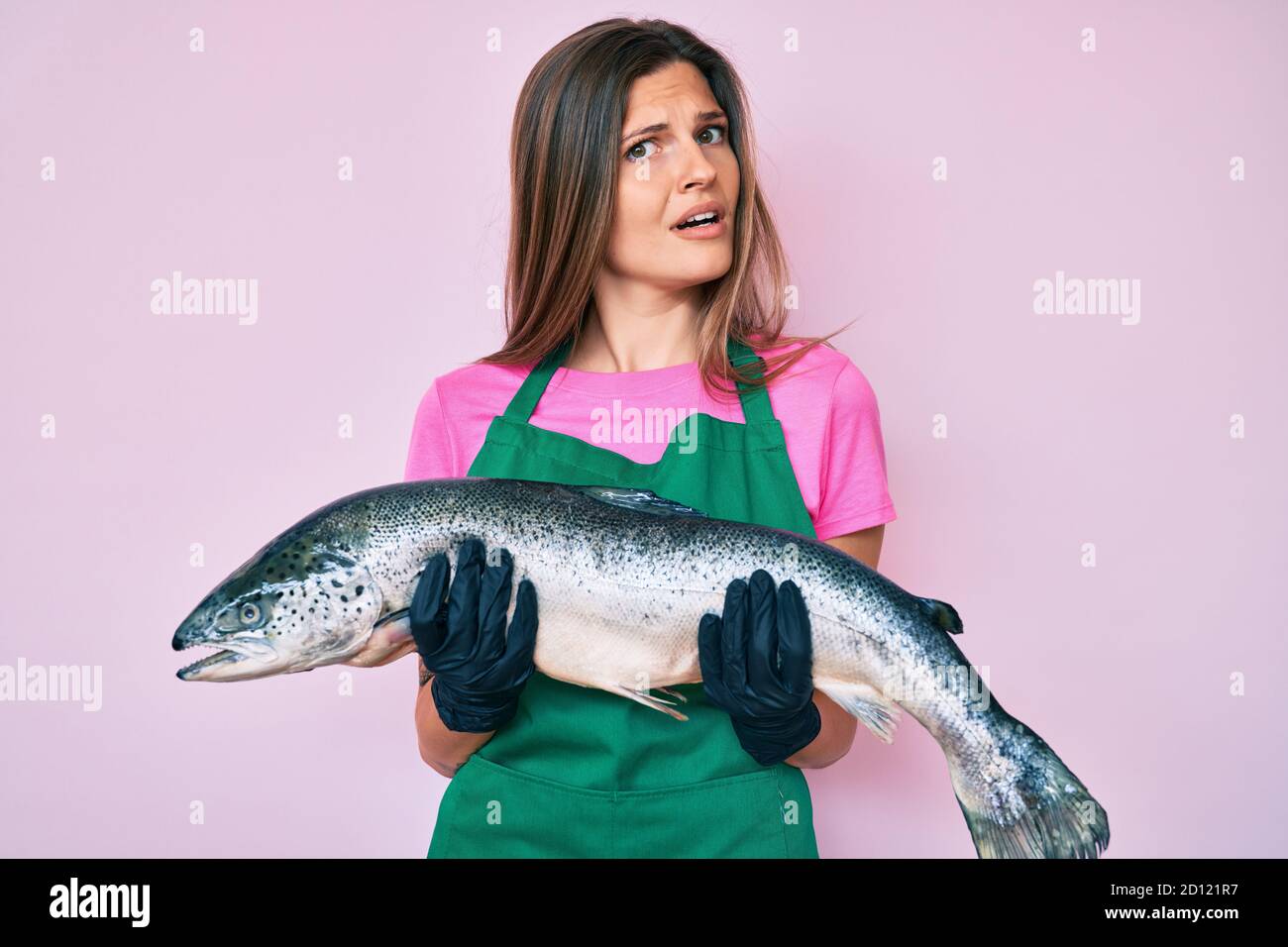 Beautiful caucasian woman fishmonger selling fresh raw salmon clueless ...