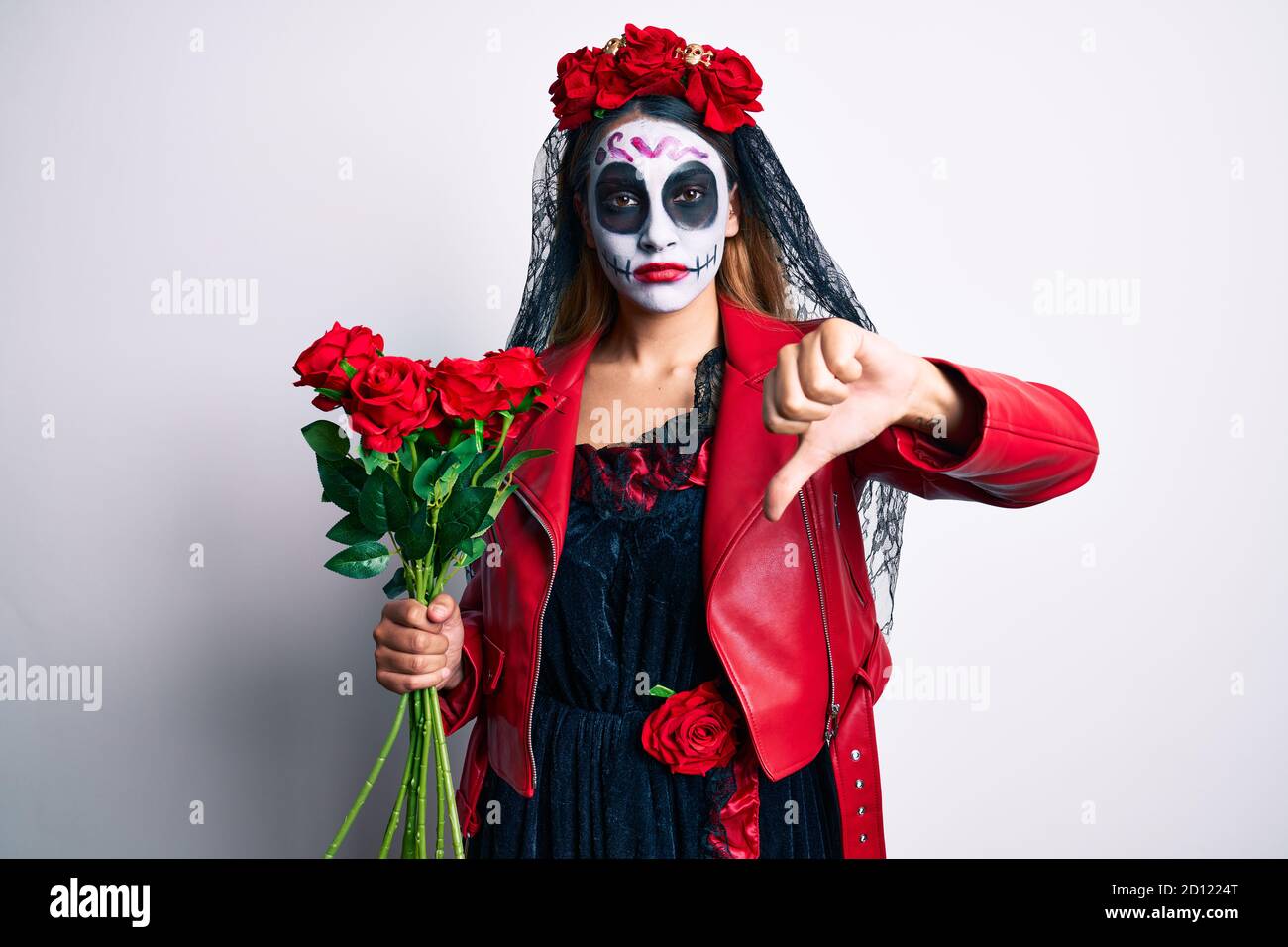 Woman wearing day of the dead costume holding roses with angry face ...