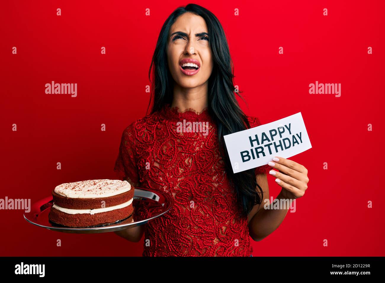Beautiful hispanic woman celebrating birthday with cake angry and mad ...