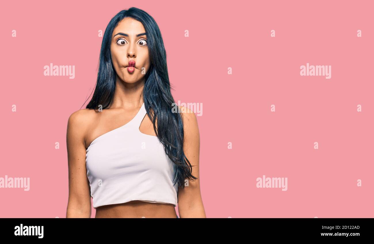 Beautiful hispanic woman wearing casual clothes making fish face with ...
