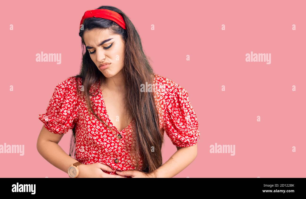 Brunette teenager girl wearing summer dress with hand on stomach ...