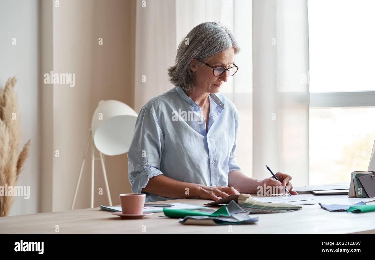 Middle aged stylish woman fashion designer drawing sketches in studio ...