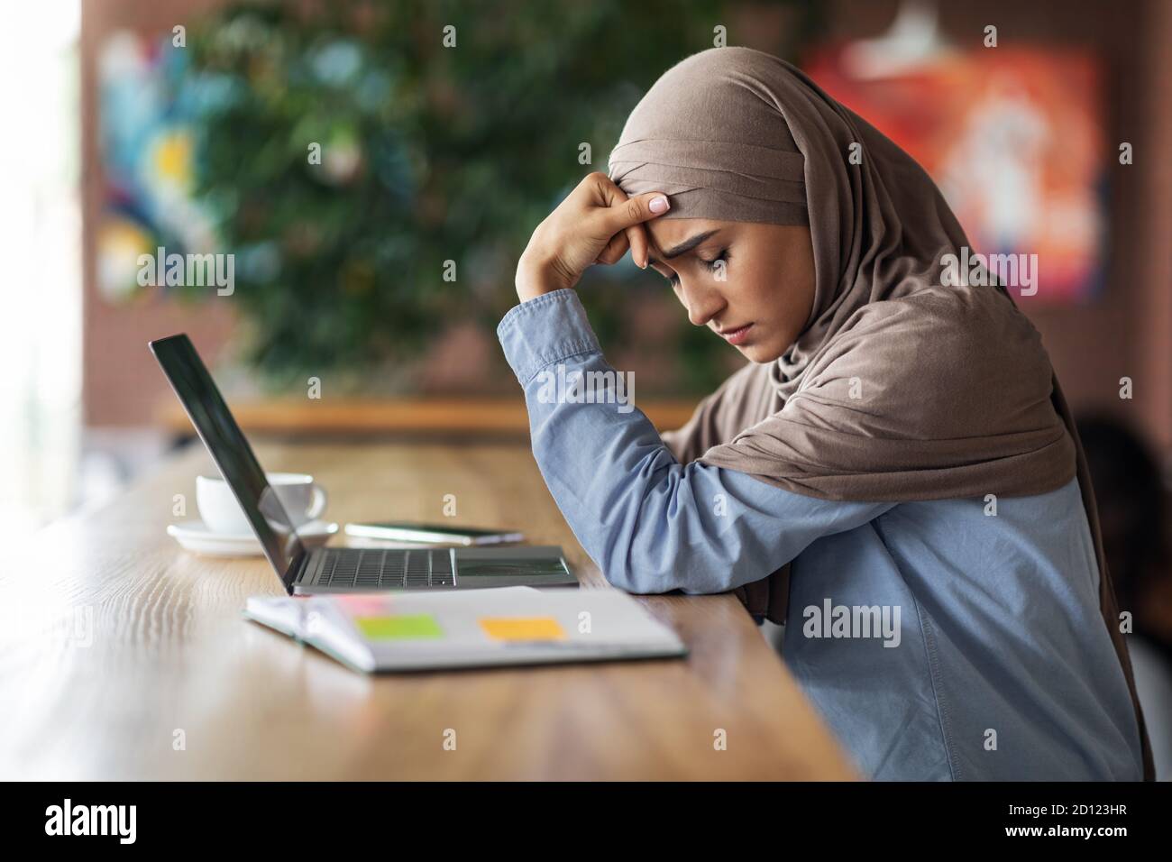 Tired muslim woman with laptop and notepad at cafe Stock Photo - Alamy