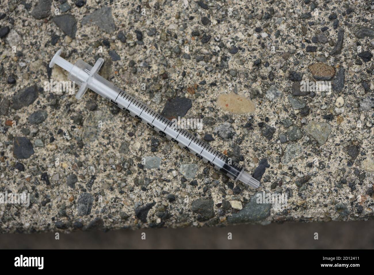 A discarded drug syringe needle lies discarded on a concrete step in ...