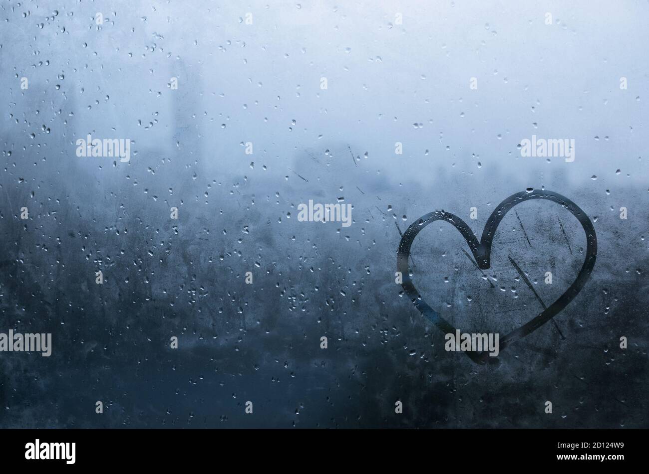 Heart painted on window which fogged up with blurred city background ...