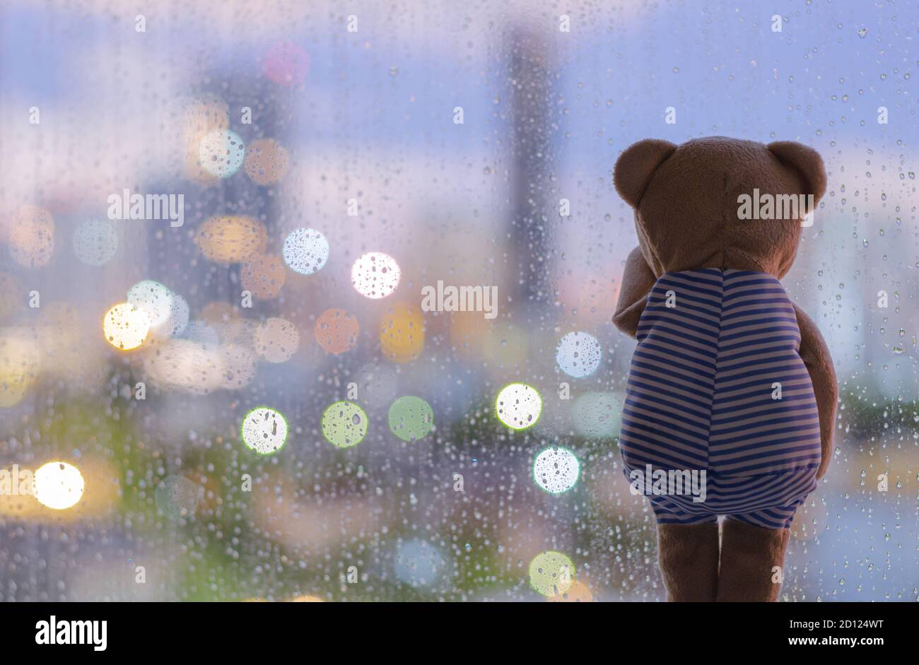 Teddy bear crying alone at window when raining with colorful bokeh ...
