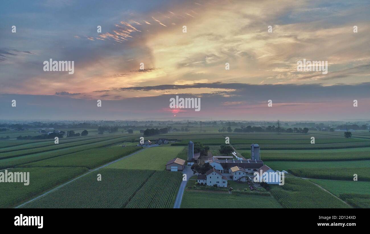 Aerial view of a summer sunset over farm lands with blue skies and red ...