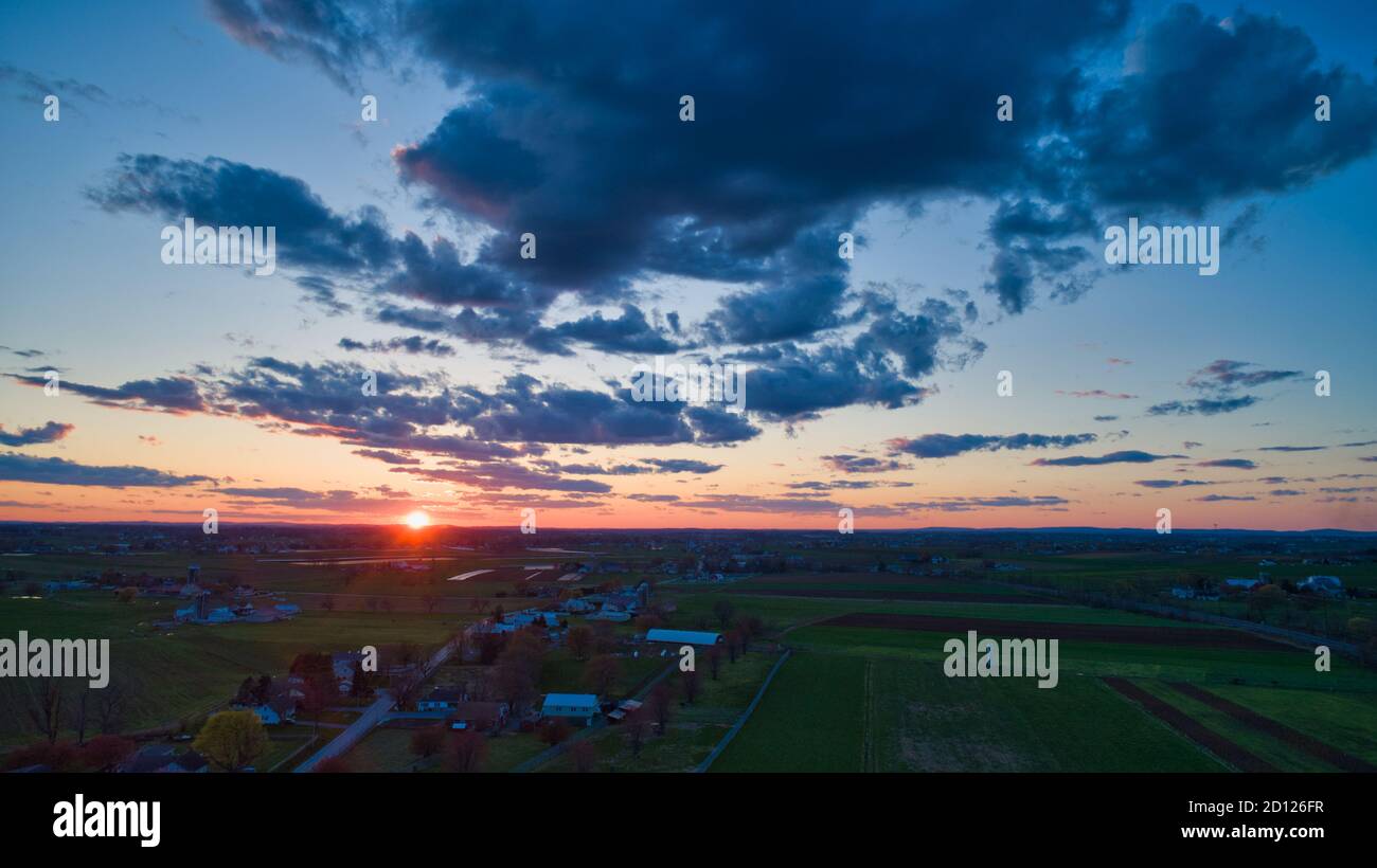 Aerial view of a Sunset over barns, silos and farmlands during the ...