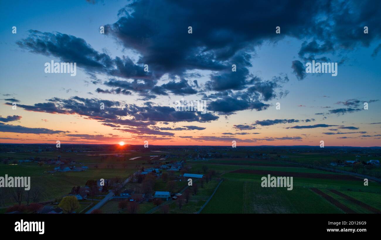 Aerial view of a Sunset over barns, silos and farmlands during the ...
