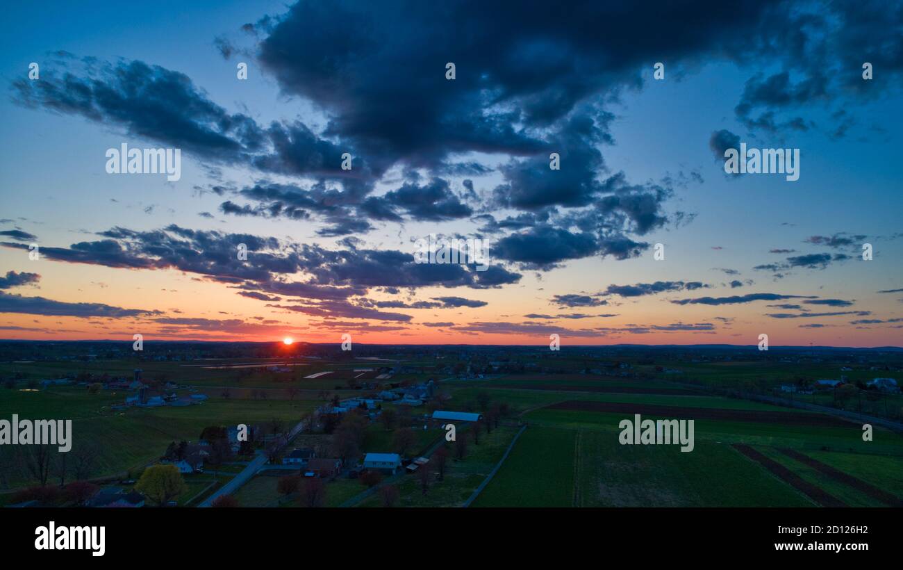 Aerial view of a Sunset over barns, silos and farmlands during the ...