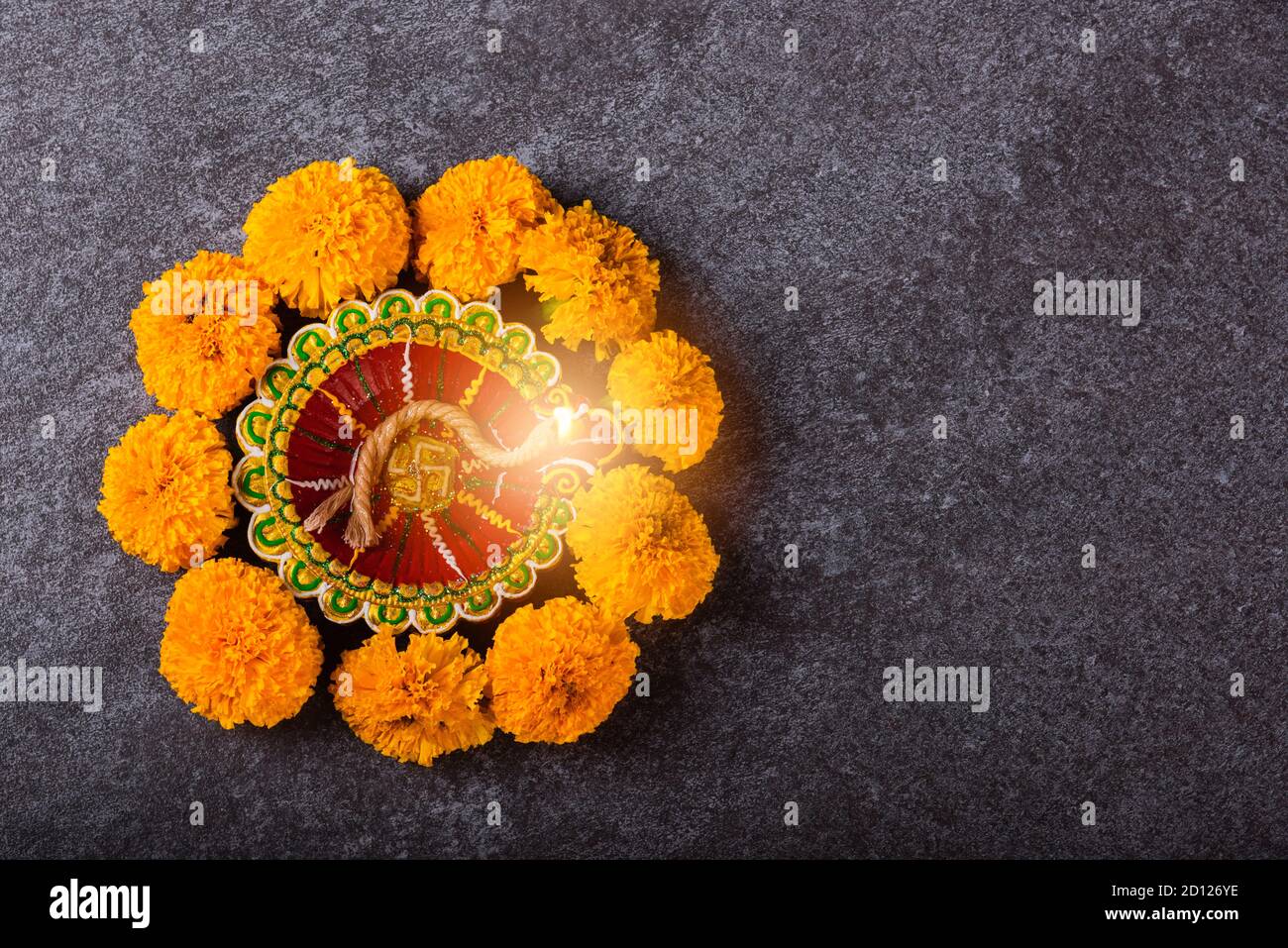 Top view overhead clay lit Diya or oil lamp and yellow flower, studio ...