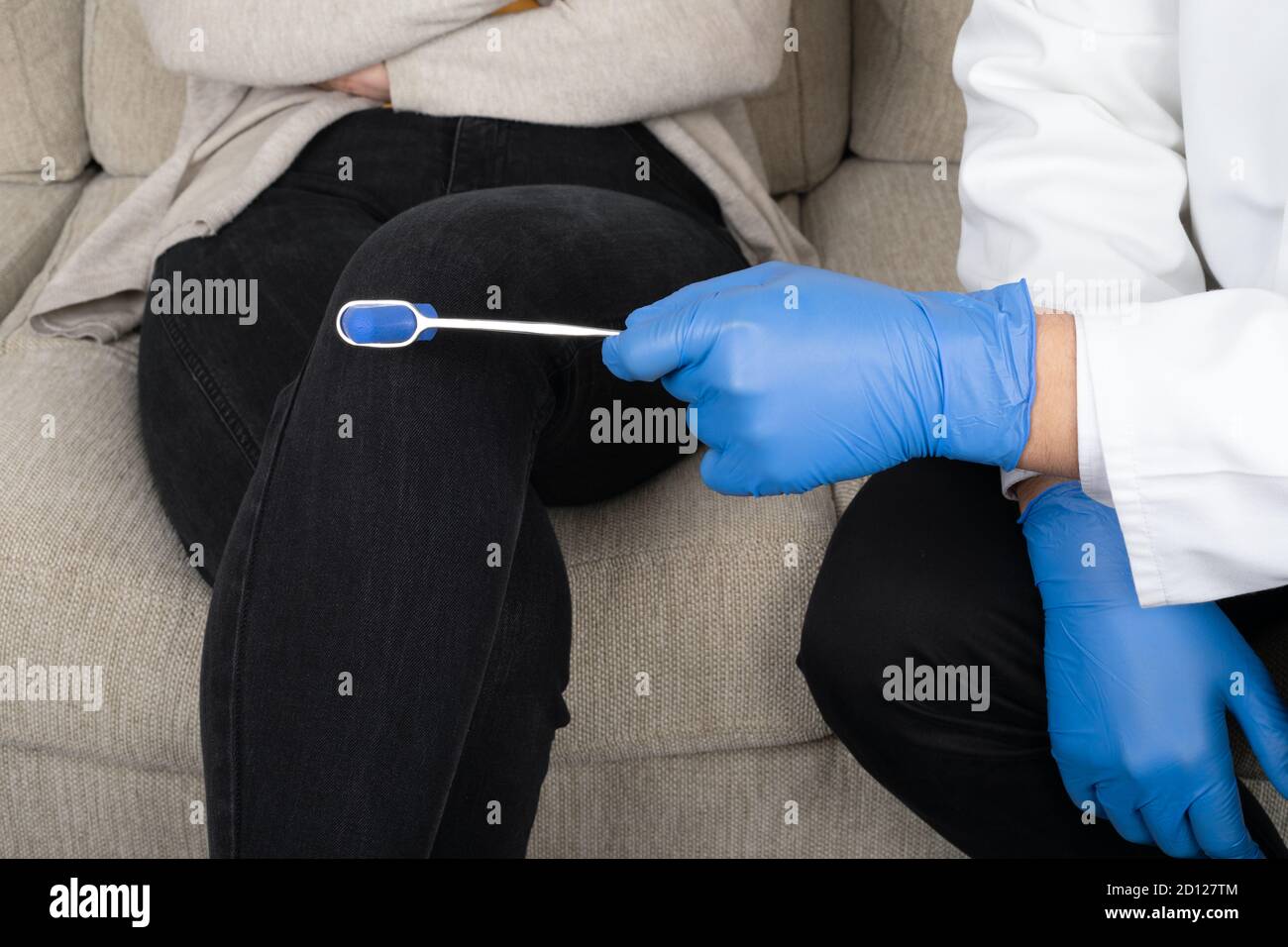 Male doctor examining the knee reflex with a test hammer Stock Photo ...