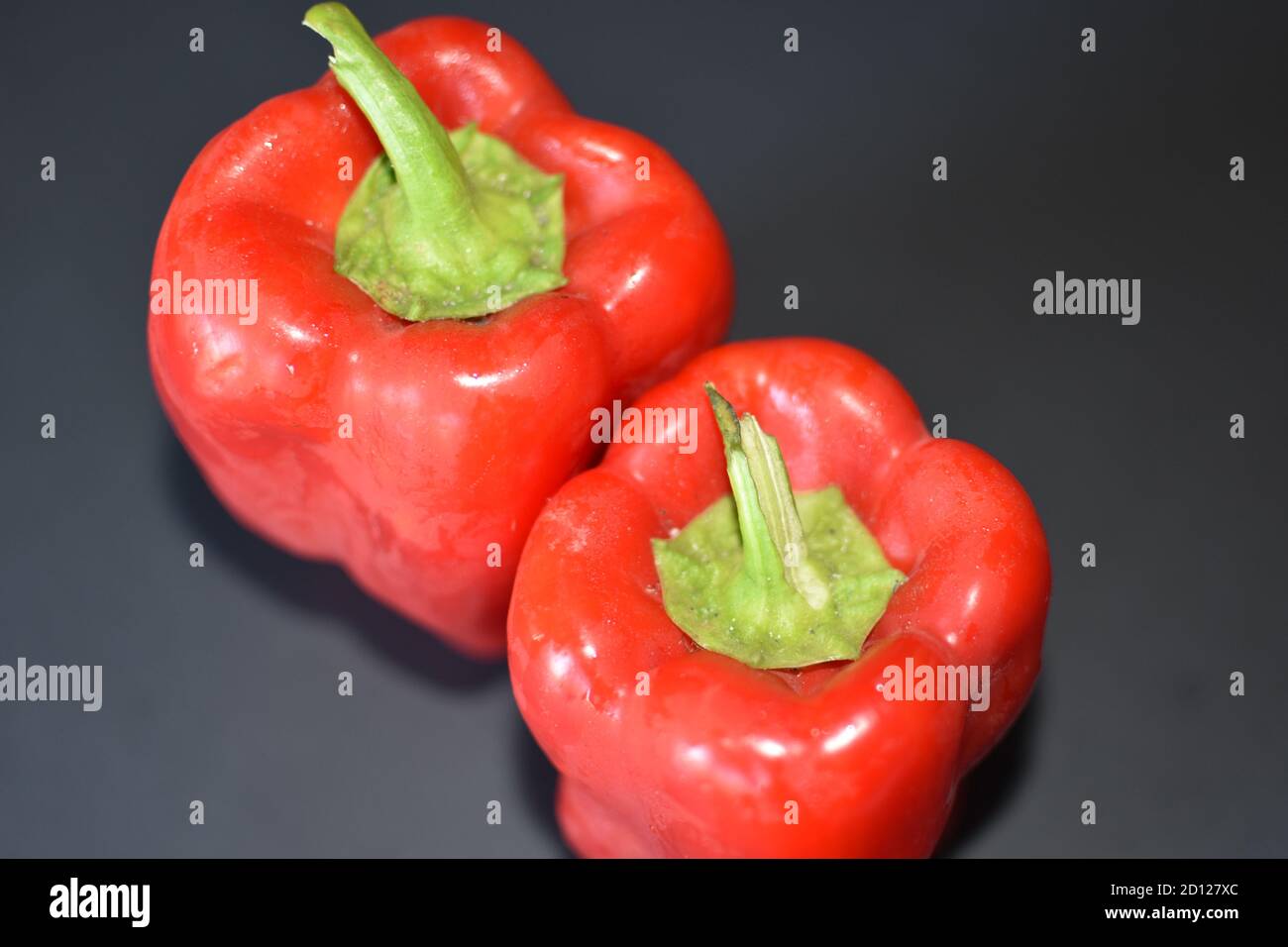 two red sweet bell peppers isolated close up on black background ...