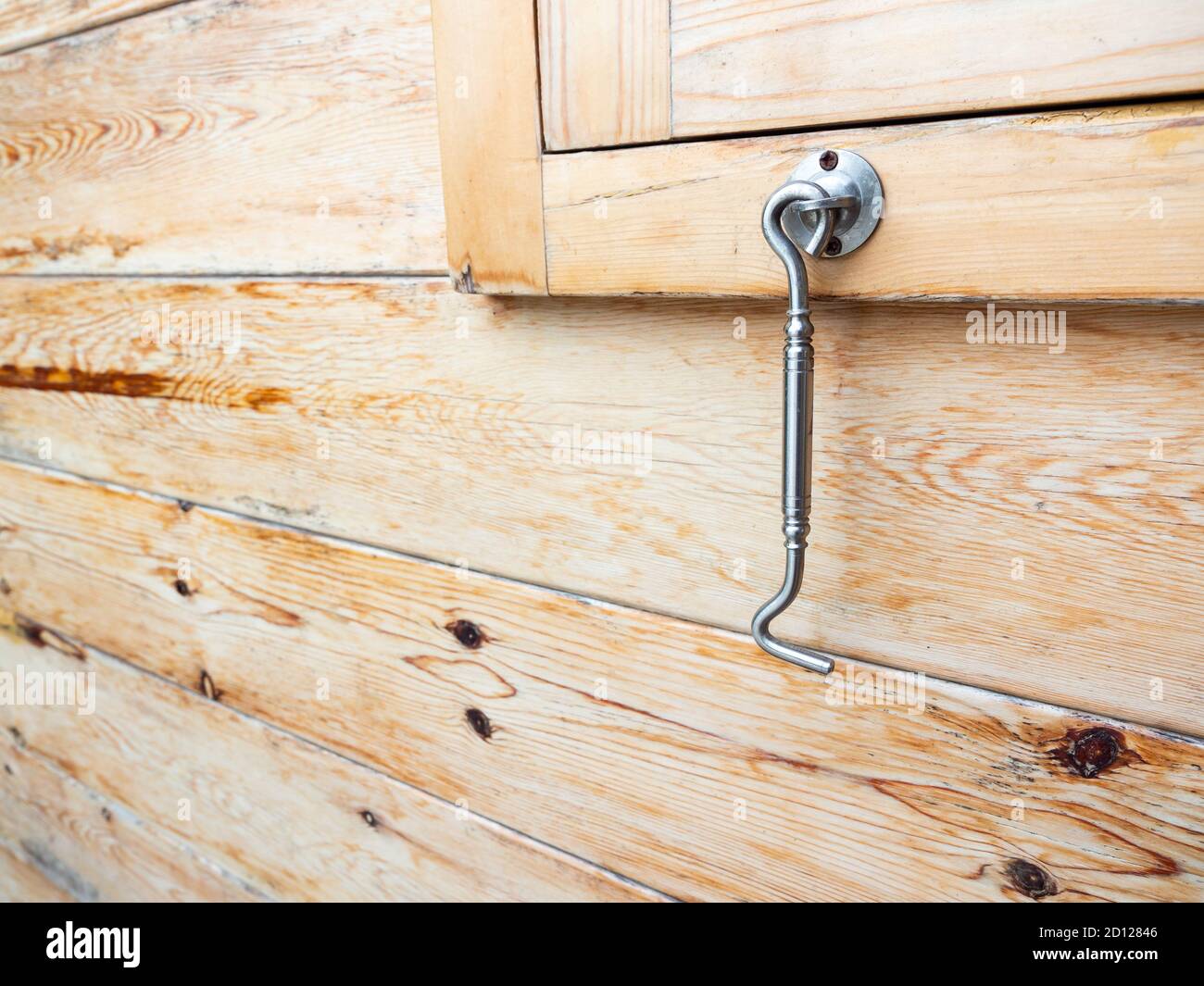 Old-fashioned window latch hook hanging on wood wall background with ...