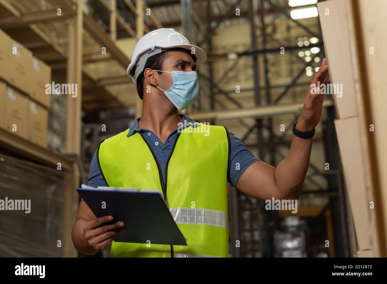 Young Indian factory warehouse worker wearing a protective face mask ...