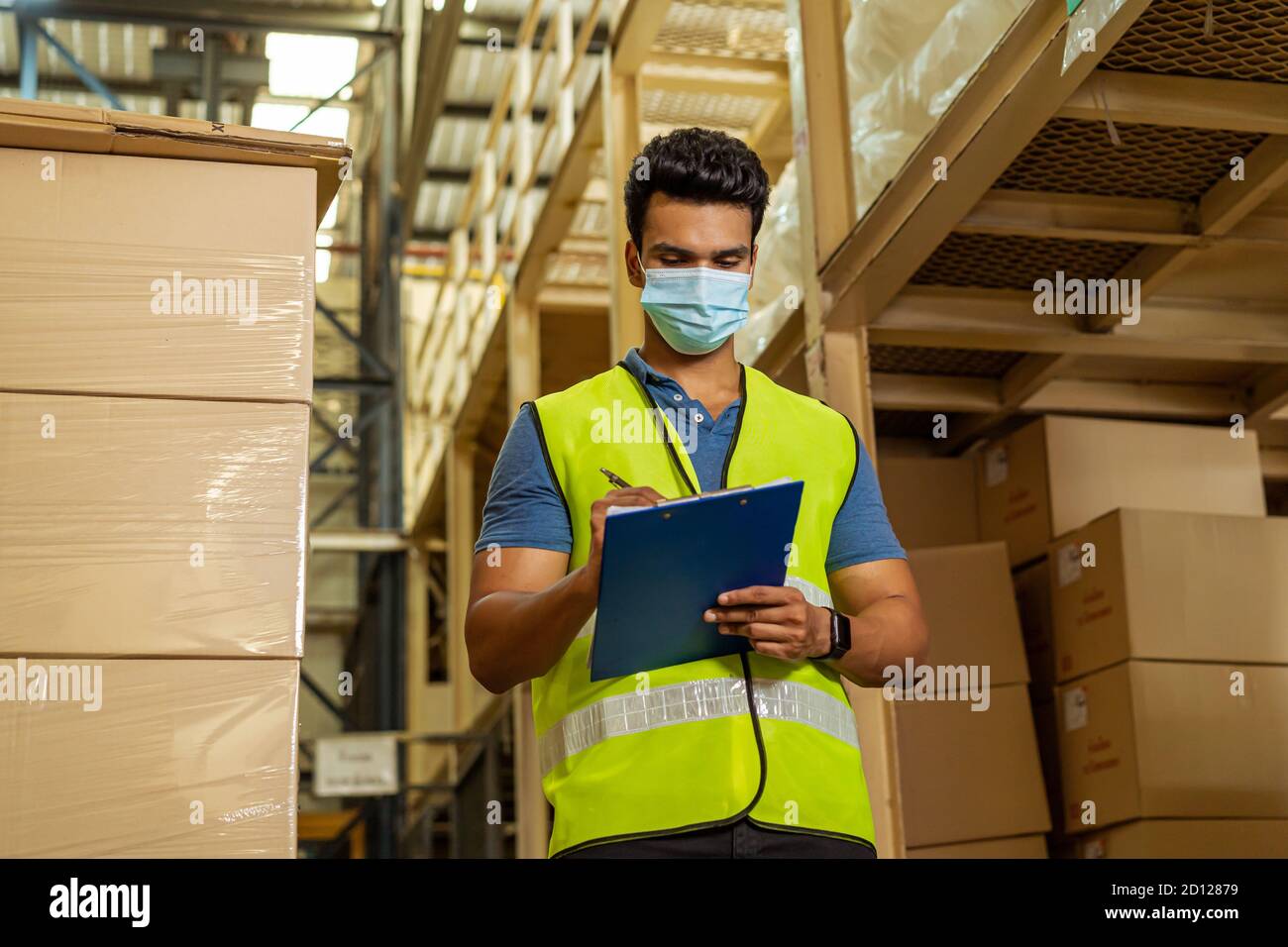 Young Indian factory warehouse worker wearing a protective face mask ...