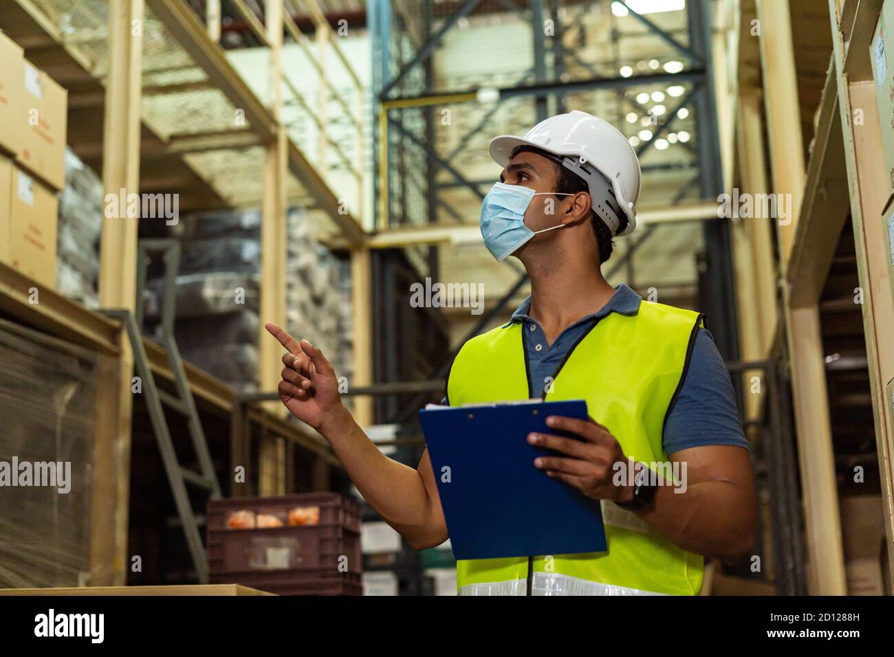 Young Indian factory warehouse worker wearing a protective face mask ...
