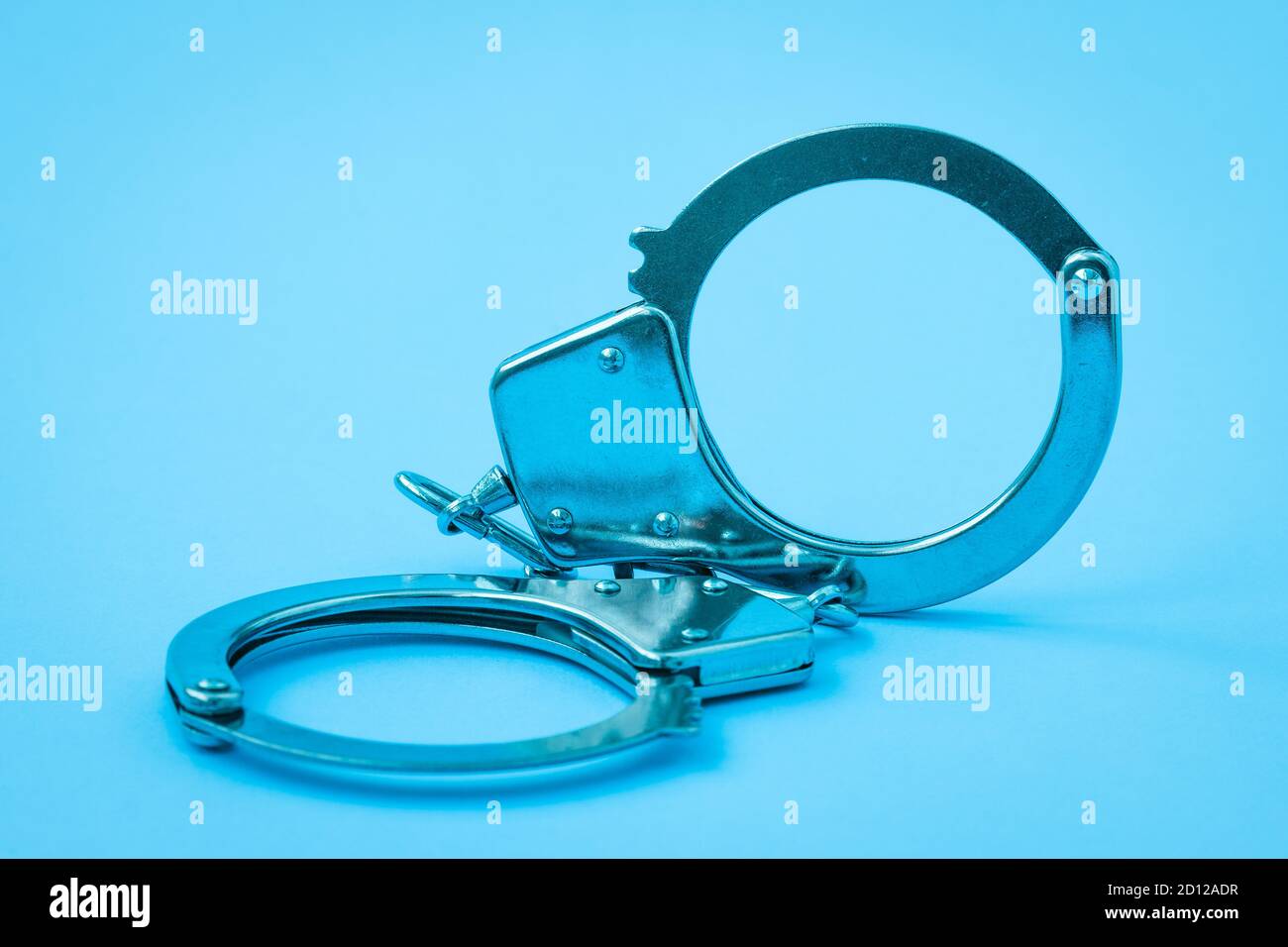 Handcuffs lying on the blue background. Blue filtered image Stock Photo ...