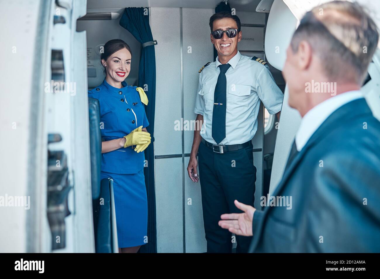 Smiling crew meeting businessman on passenger plane Stock Photo - Alamy