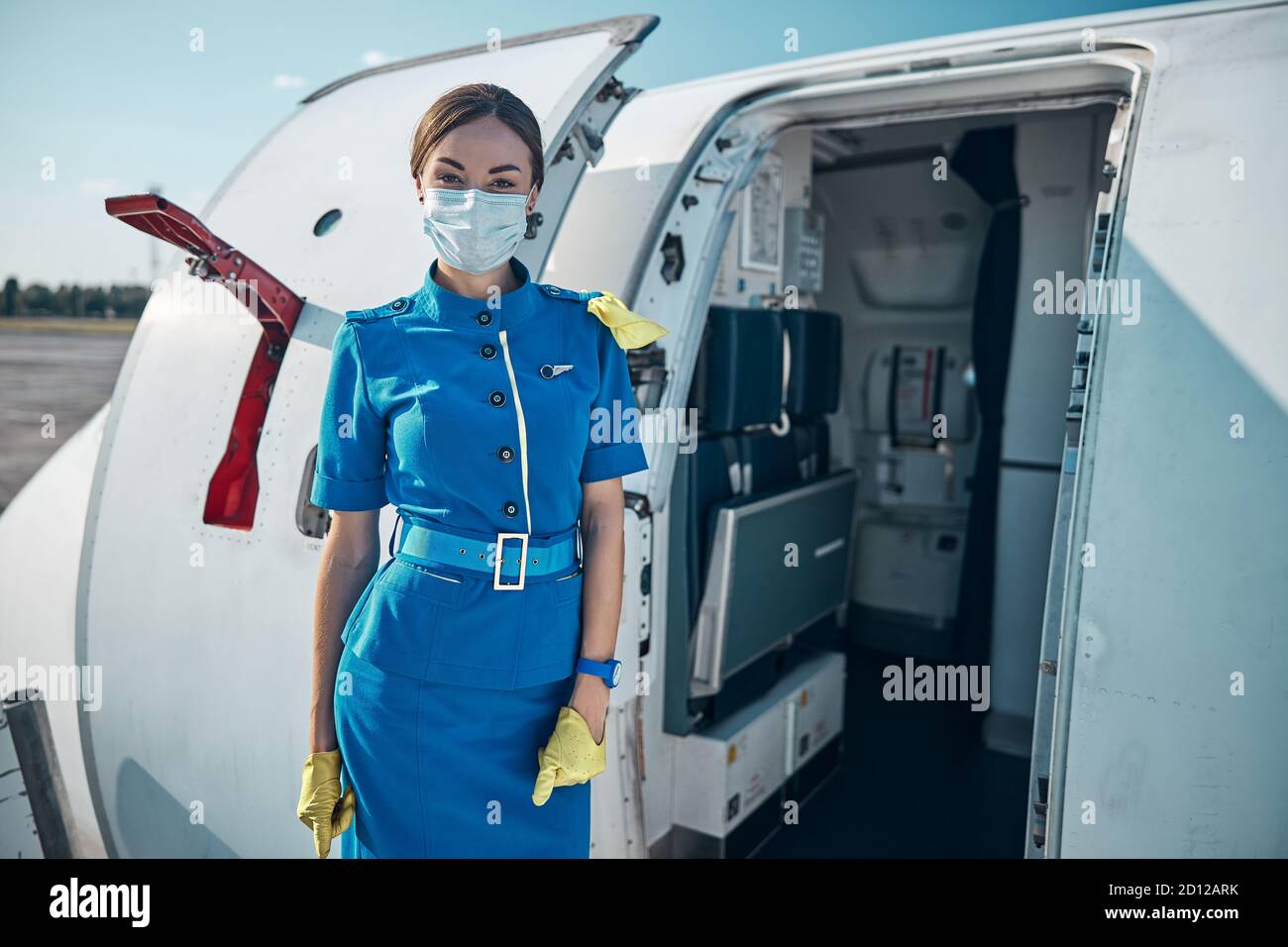 Pretty stewardess welcoming passengers to comfortable plane Stock Photo ...