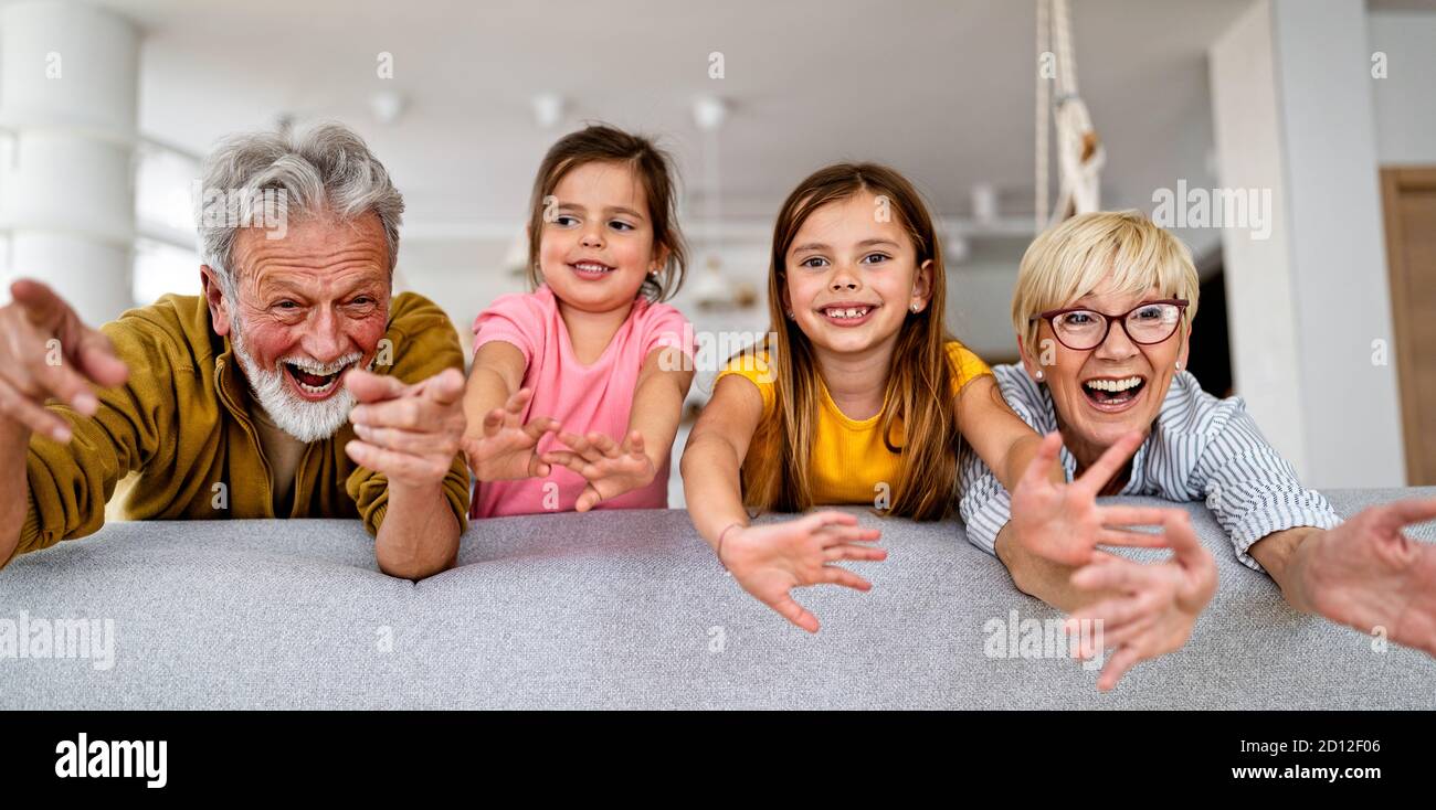 Portrait of happy elderly couple and grandchildren playing together ...