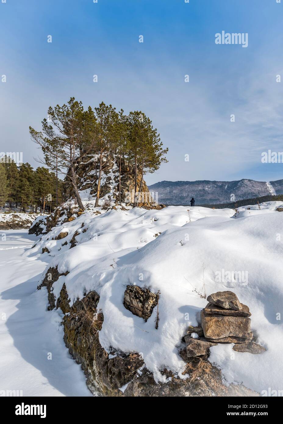 Rocky island covered with snow and pine trees in the middle of a frozen ...