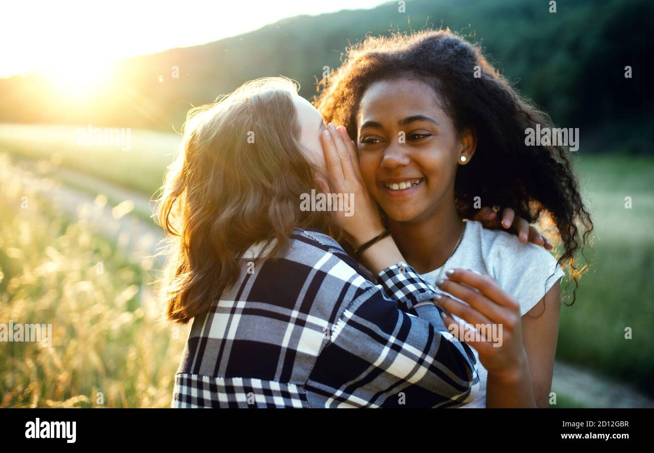 Girl whispering into teenage girls ear hi-res stock photography and ...