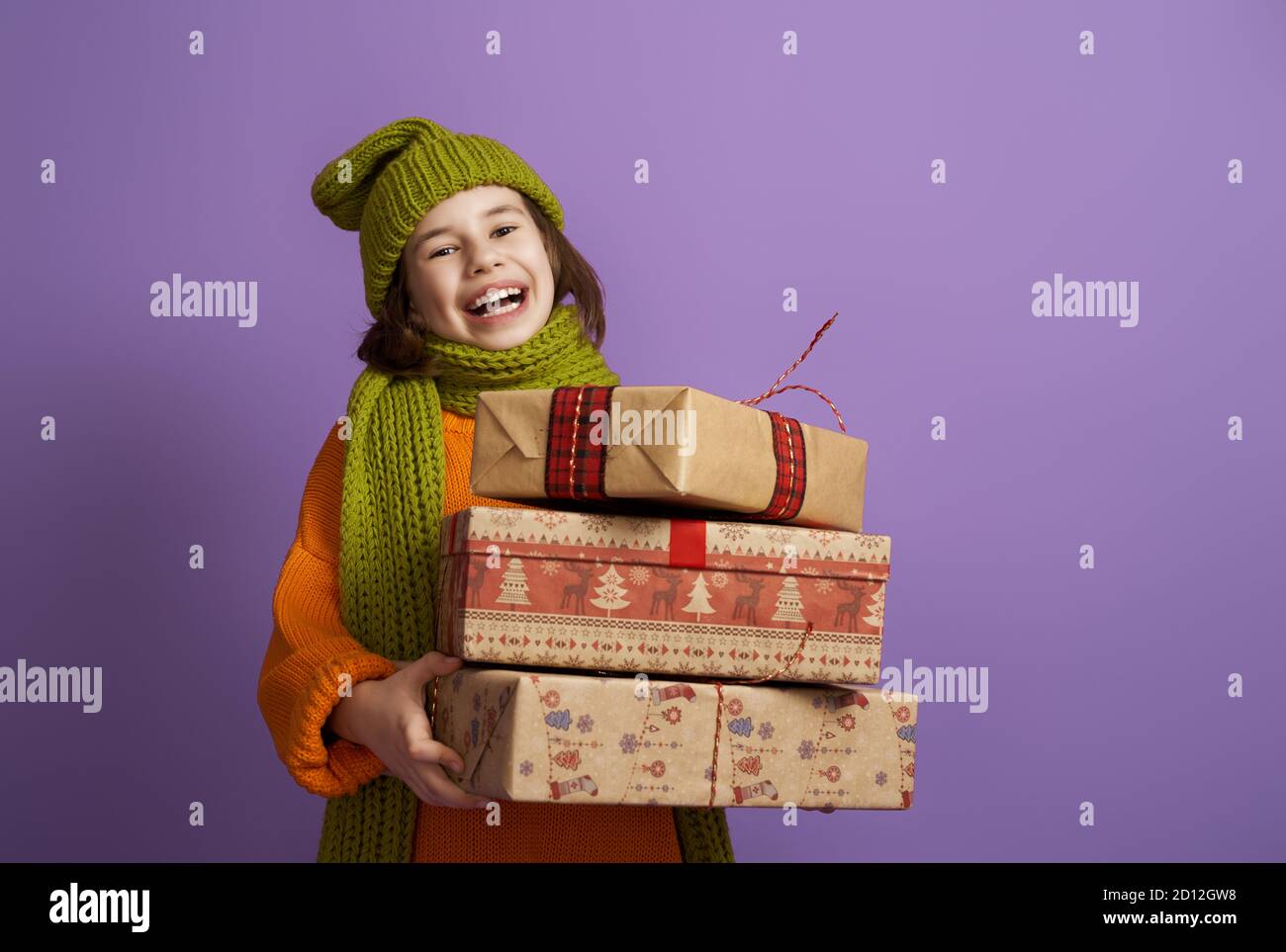 Happy little girl with Christmas gift on bright color background ...