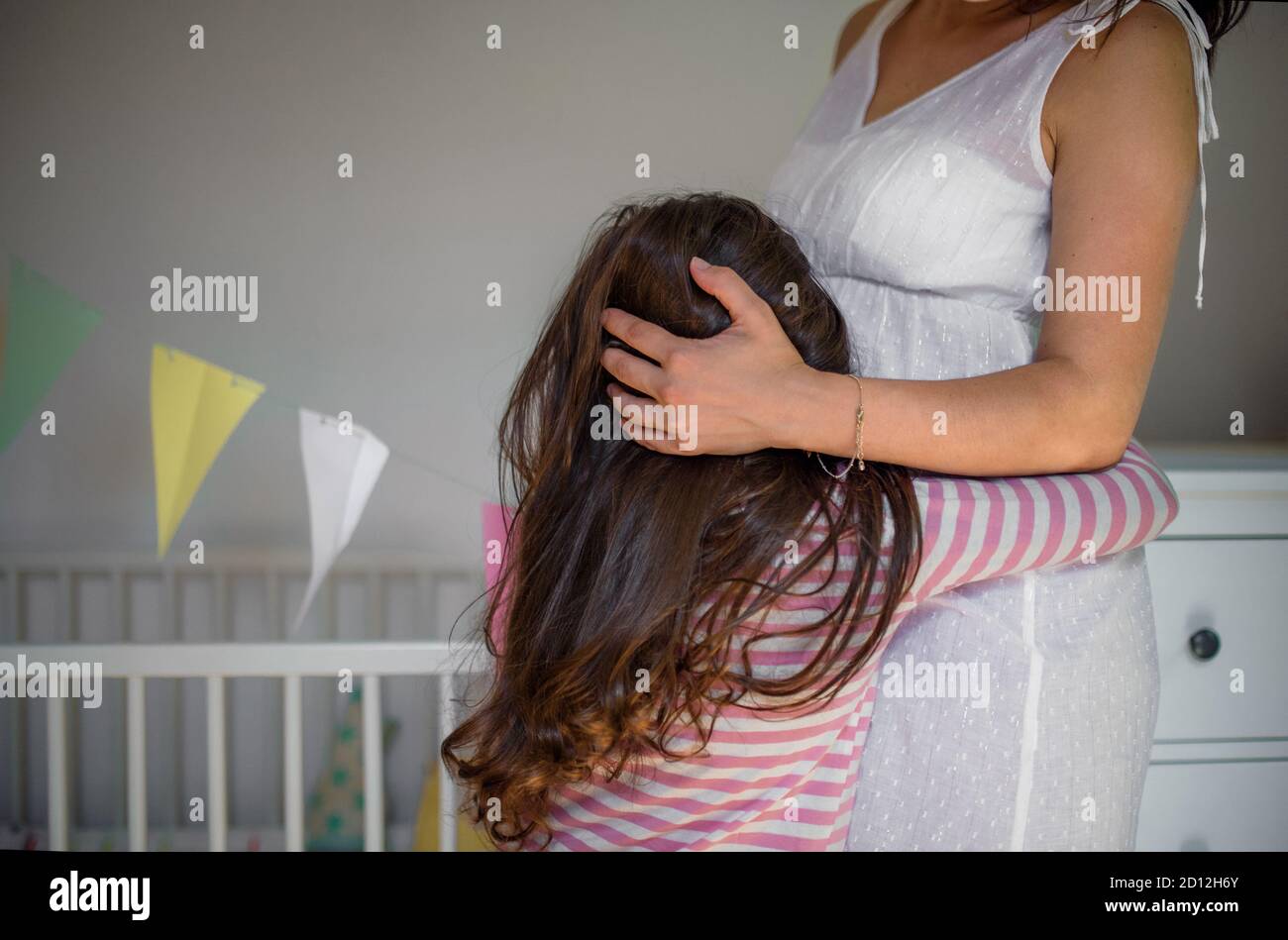 Portrait Of Pregnant Woman With Small Daughter Indoors At Home Hugging