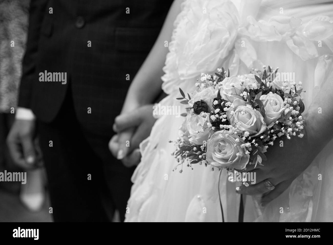 The bride and groom hold each other's hands, a gold ring on the bride's ...