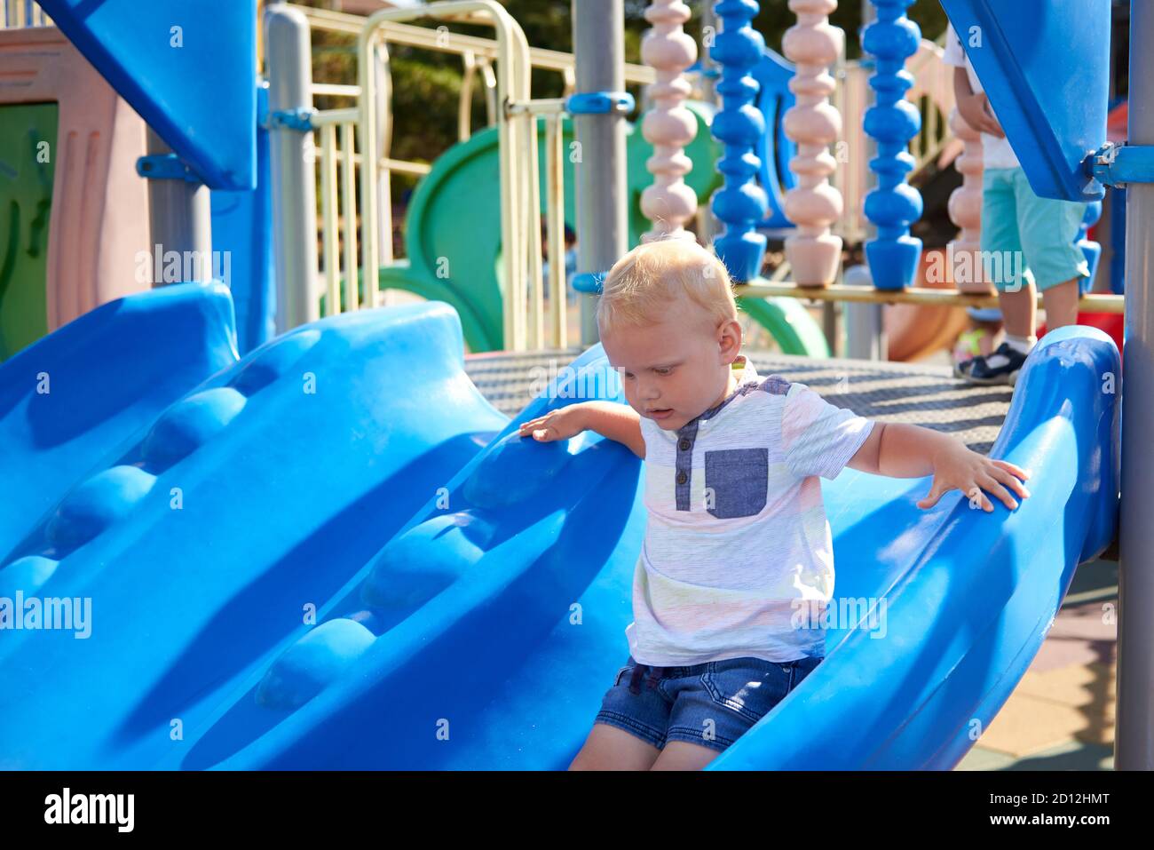 A small caucasian boy slides down a slide in the playground Stock Photo ...