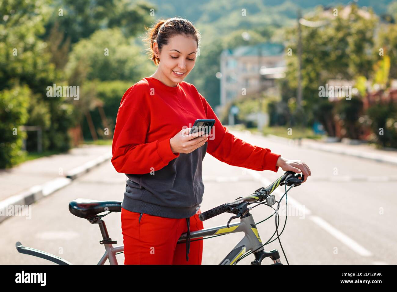 Activity. A young beautiful woman uses her phone while riding a Bicycle ...