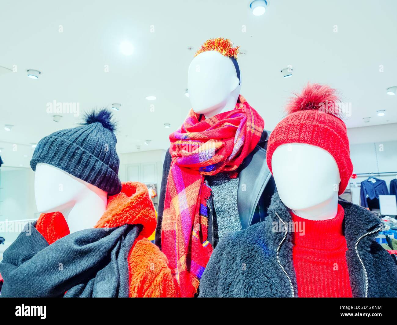 Three faceless mannequins in warm clothes in a store with a white ...