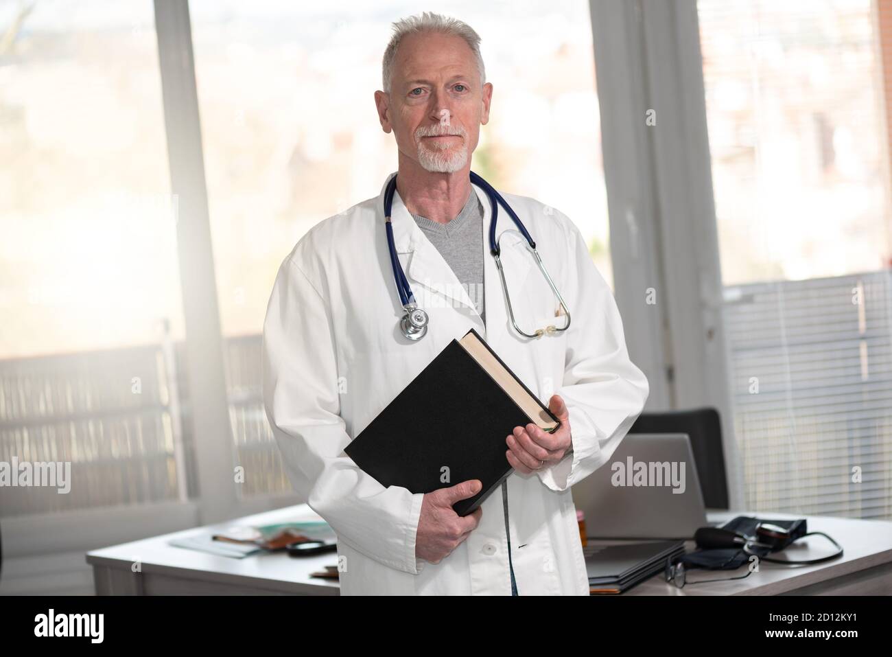 Doctor standing and holding a medical textbook Stock Photo - Alamy